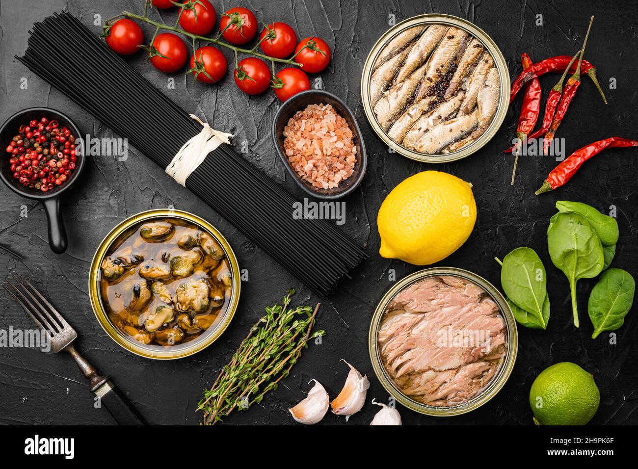 Opened cans conserve with tuna mussel, sprats, on black dark stone ...