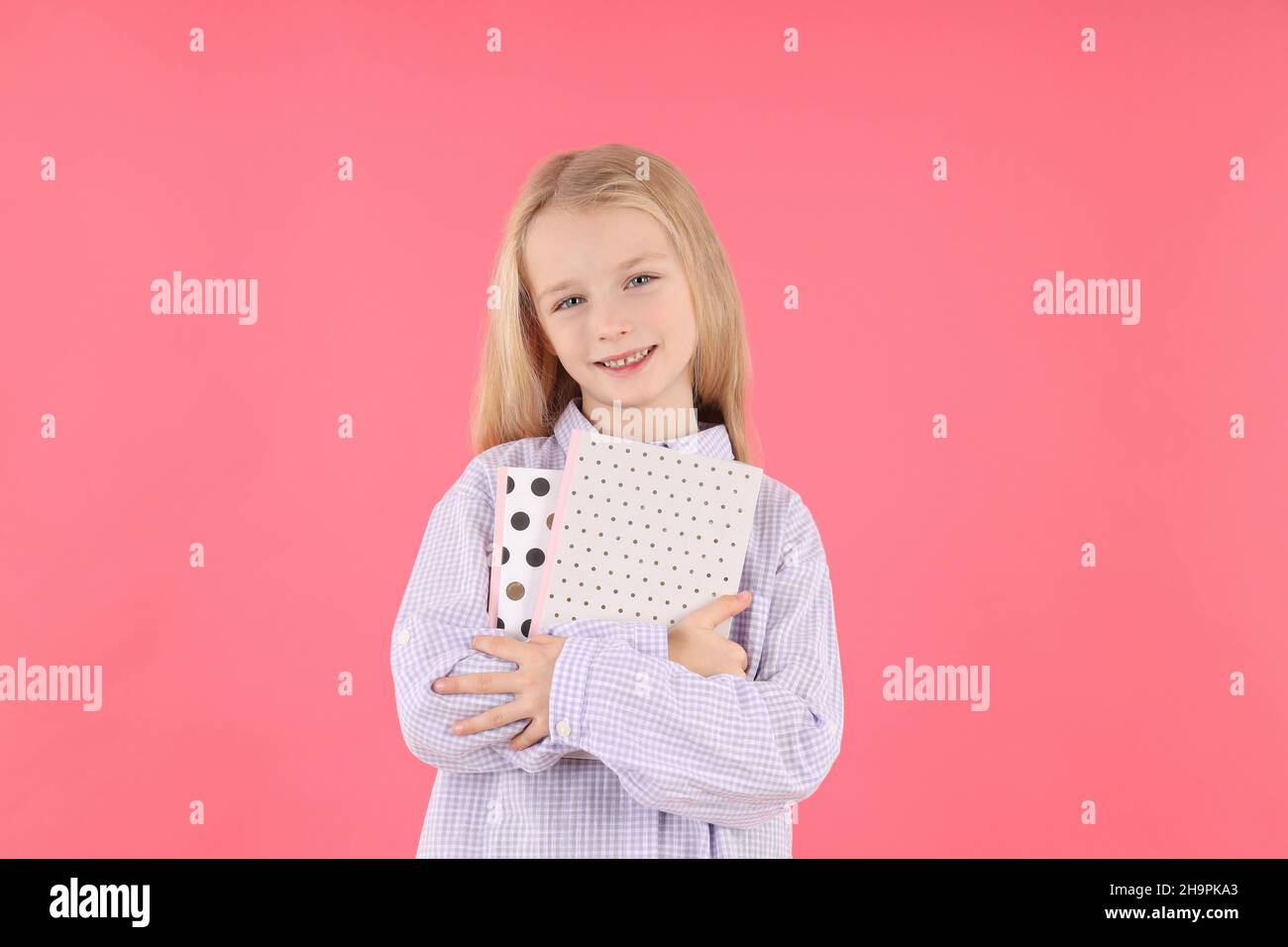 Cute little girl with notebooks on pink background Stock Photo - Alamy