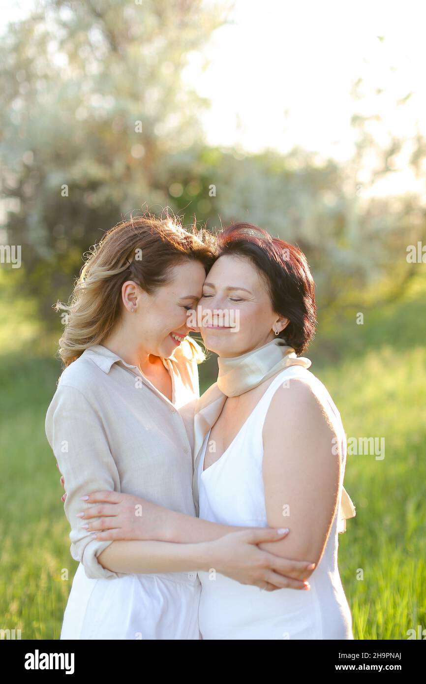 Portrait of girl hugging mother in park and wearing white clothes Stock Photo - Alamy