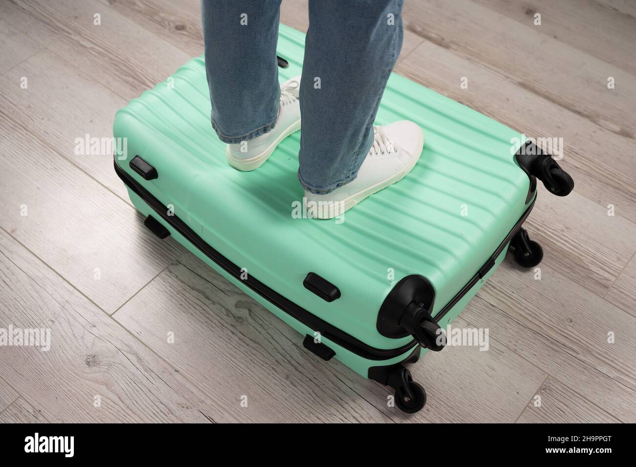 Woman standing with her feet on a suitcase Stock Photo - Alamy