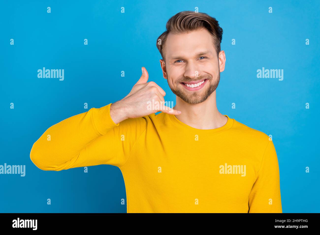Photo of young guy happy positive smile show finger call phone sign ...