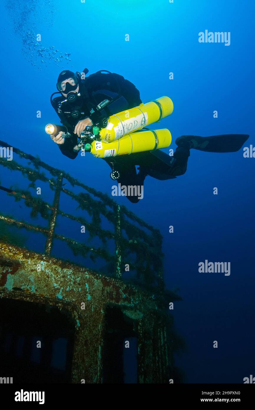 Diver swims over shipwreck has special equipment carries stage tanks ...