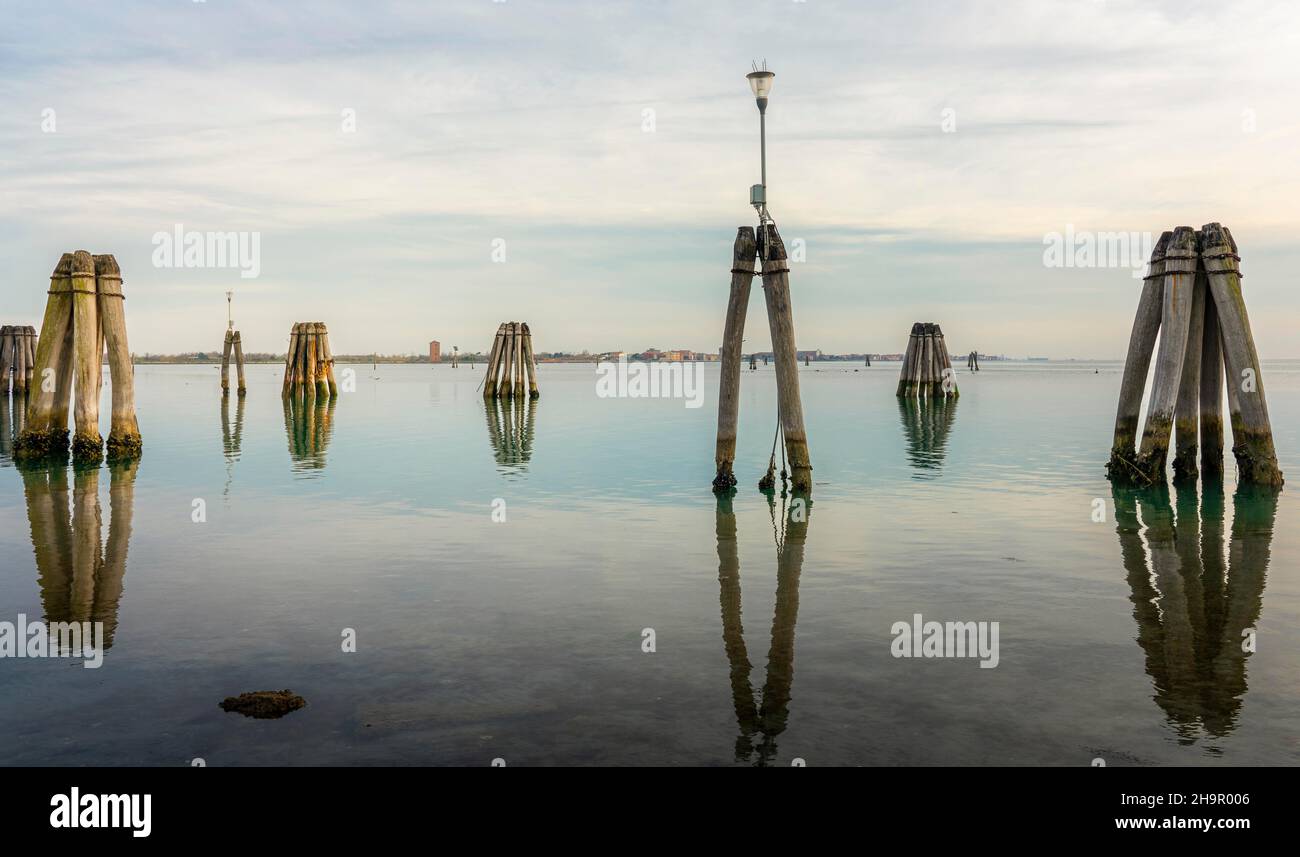 Wooden posts with lanterns at the entrance to a harbour, Venice, Italy ...