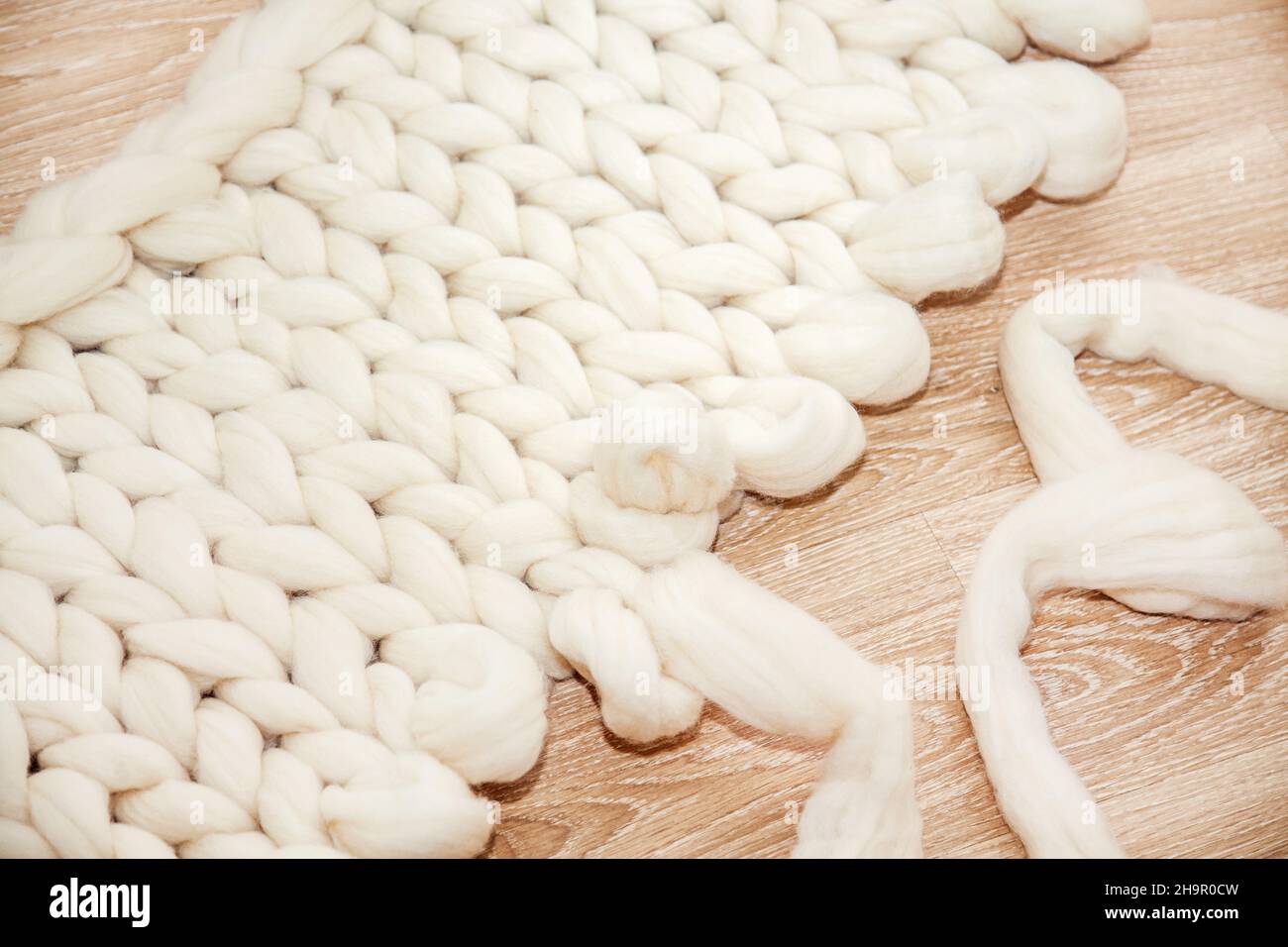 The process of knitting a plaid of large knitting from merino wool ...