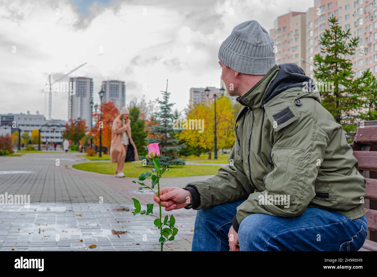 A guy on a bench with a rose meets his beloved, who throws him Stock ...