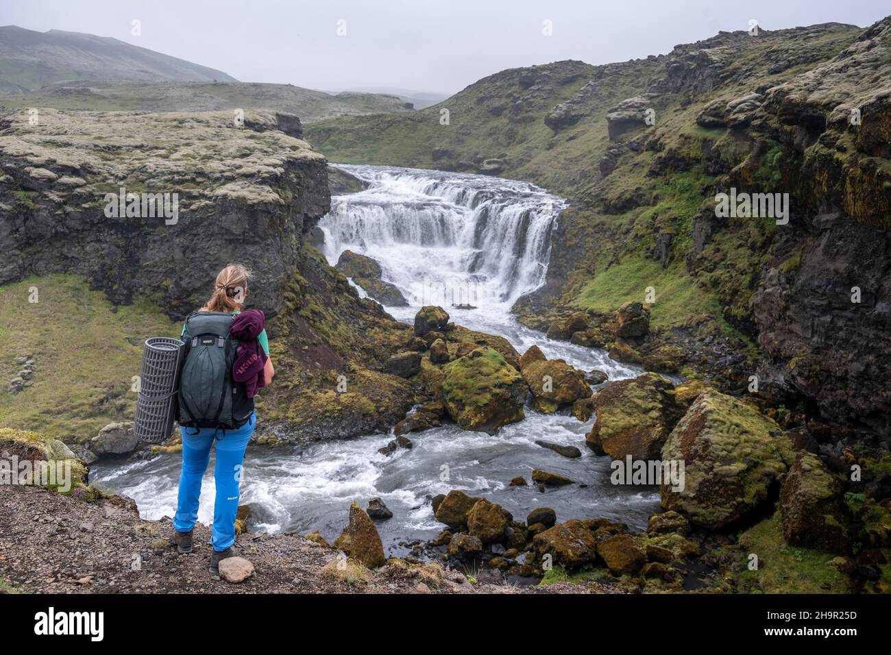 Hiker with large hiking backpack in front of waterfall, landscape at ...
