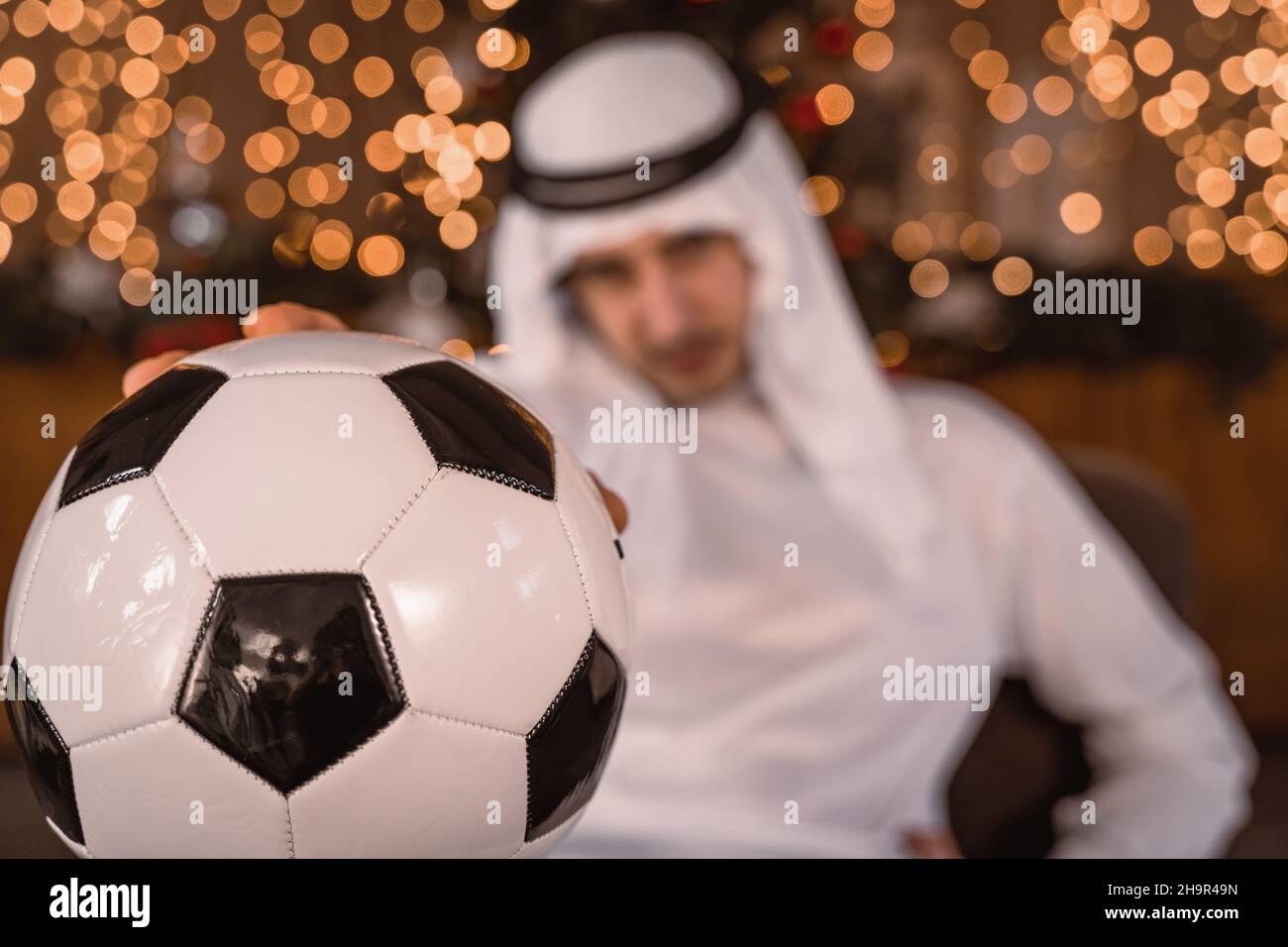 portrait of arab businessman showing a soccer ball in front of lights ...