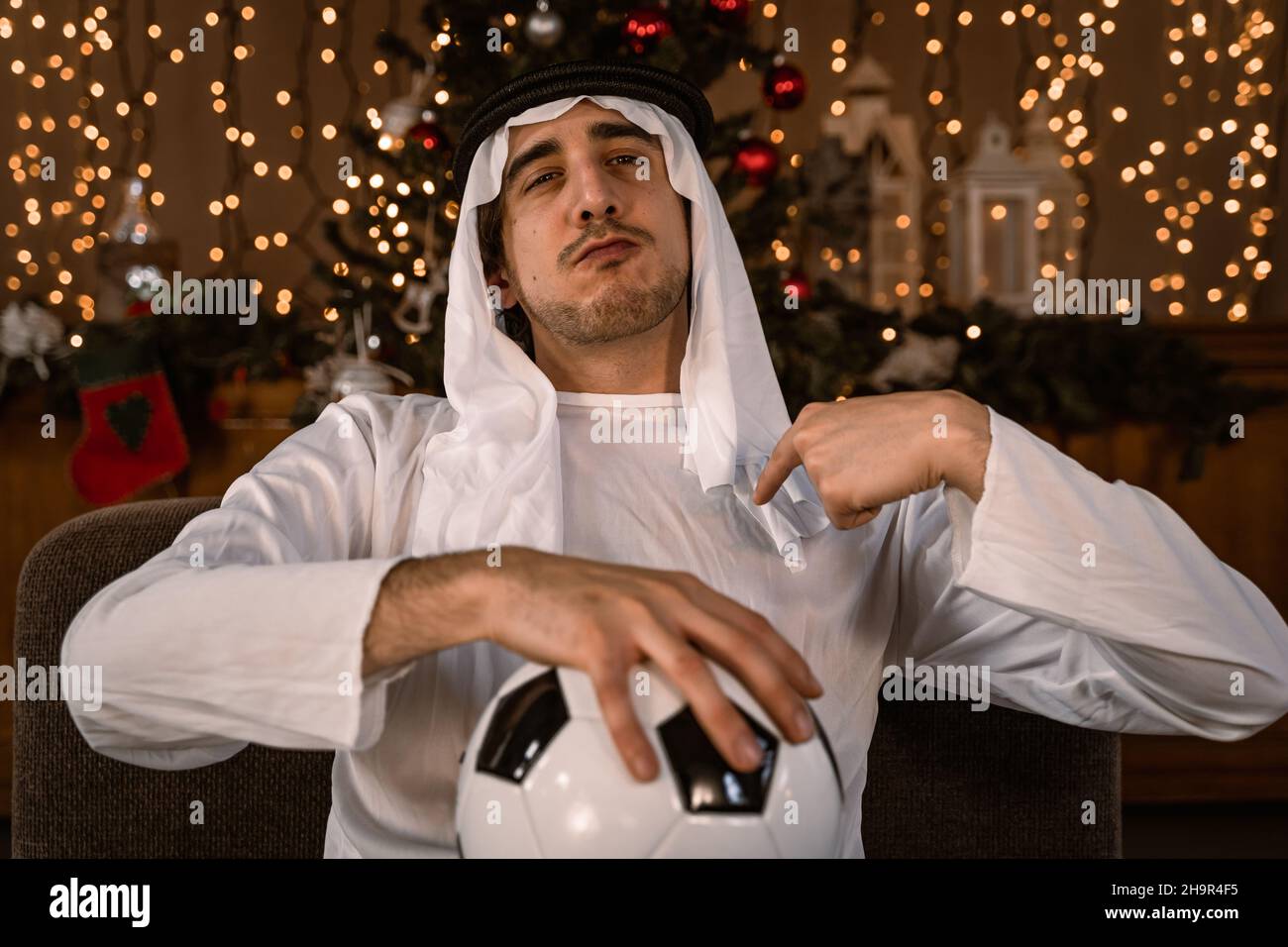 portrait of arab businessman showing a soccer ball in front of lights ...
