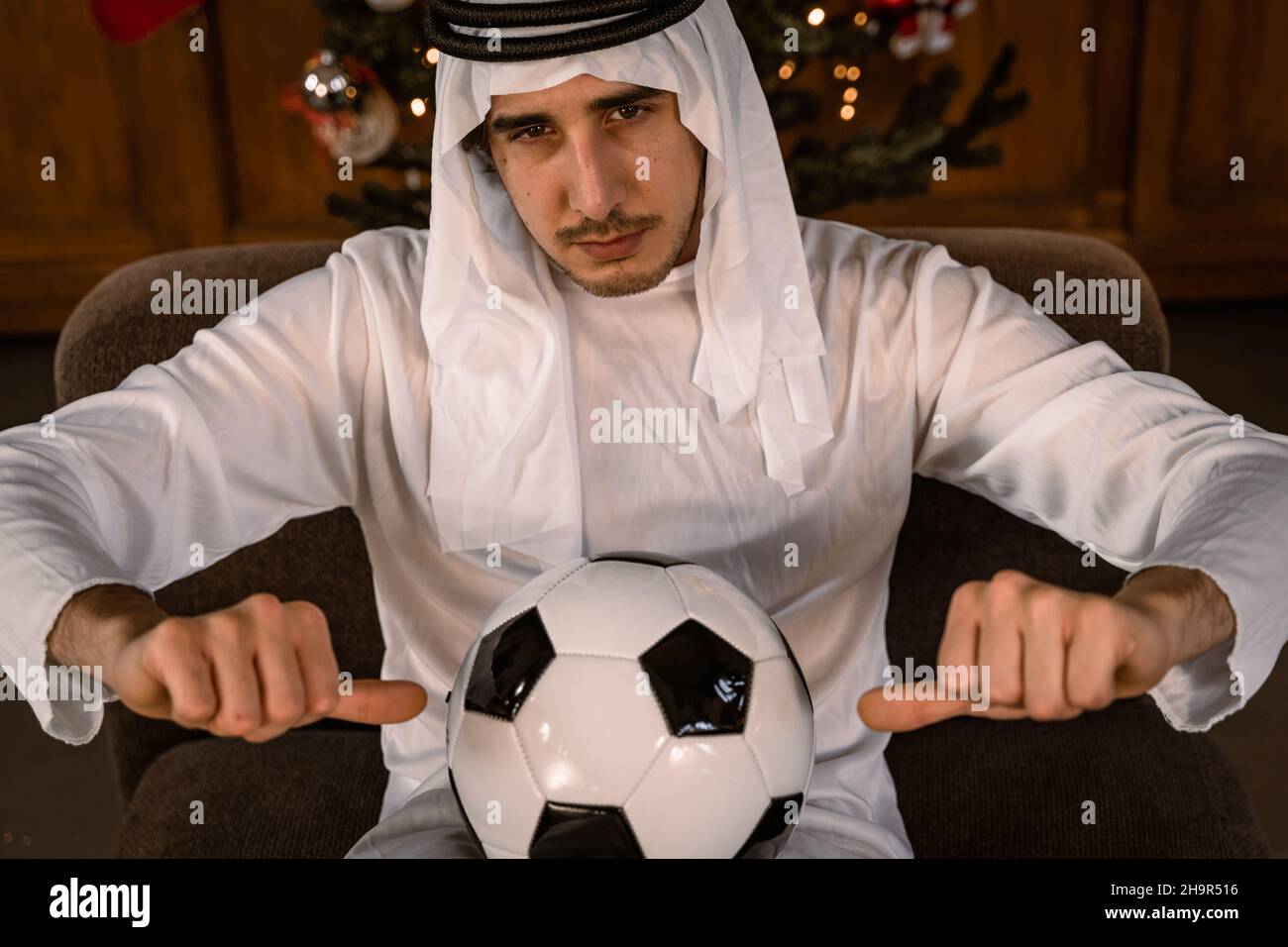 portrait of arab businessman showing a soccer ball in front of lights ...