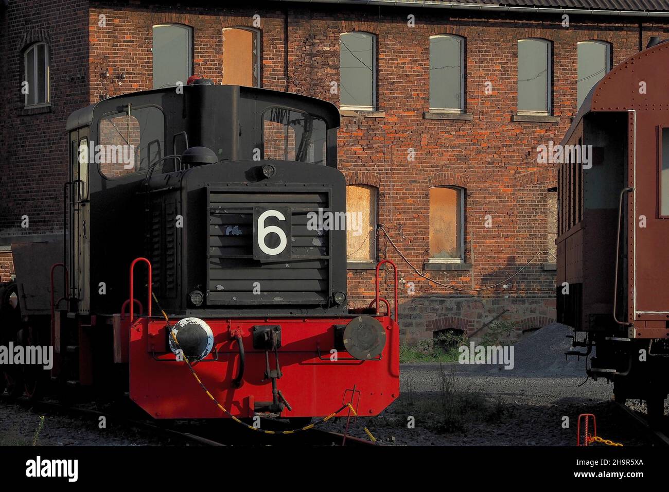 Diesel locomotive with wagon in front of disused station, rail vehicle ...