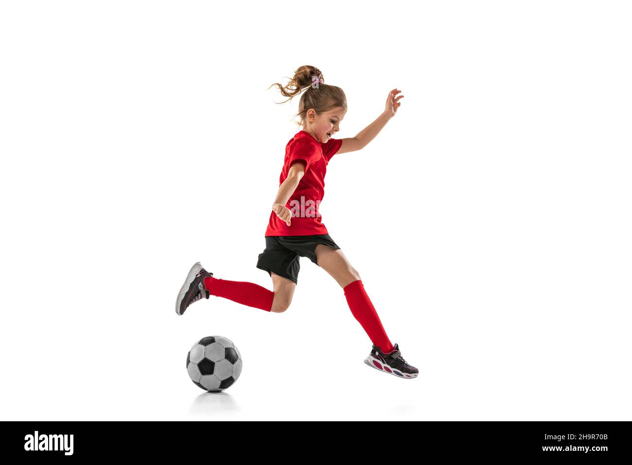 Full-length portrait of little girl, child, training, playing football ...