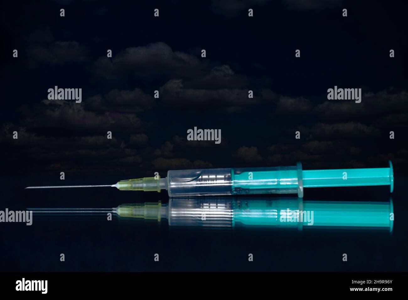 Hypodermic syringe lying on a mirror, studio photography with dark ...