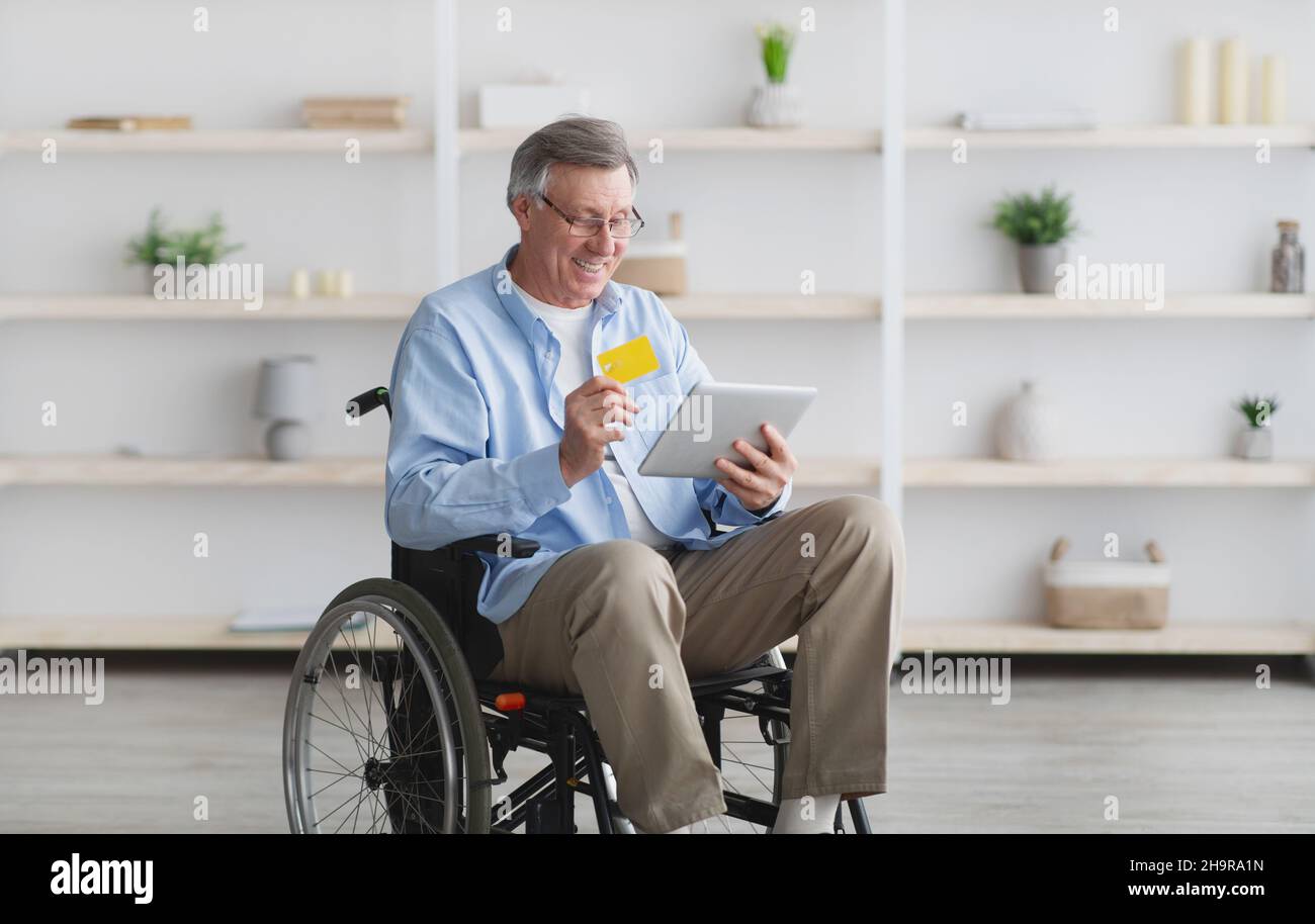 Happy senior man in wheelchair shopping online with tablet computer and ...
