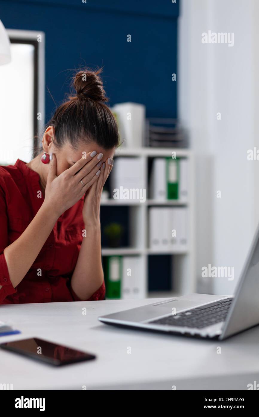 Sad entrepreneur in red shirt holding face in palms. Disappointed ...