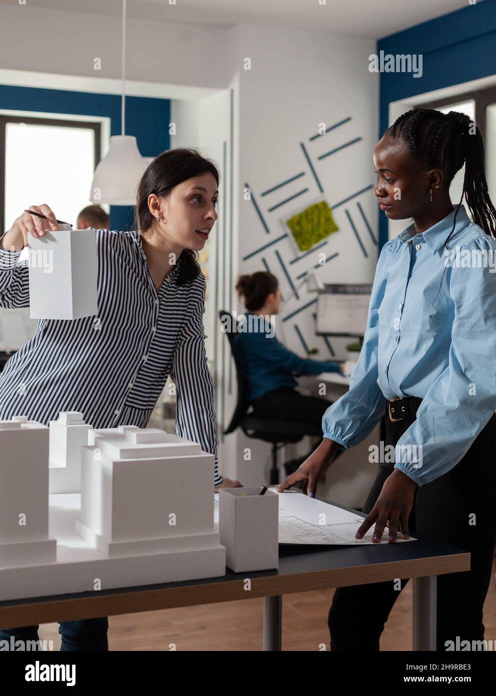 Architect presenting foam scale building model to engineer coworker ...