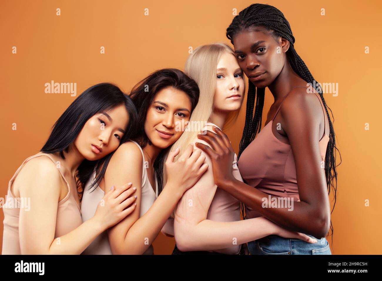 young pretty asian, caucasian, african woman posing cheerful together on brown background ...