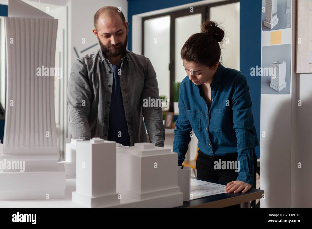 Architectural engineers doing teamwork reading construction plans standing next to table with ...