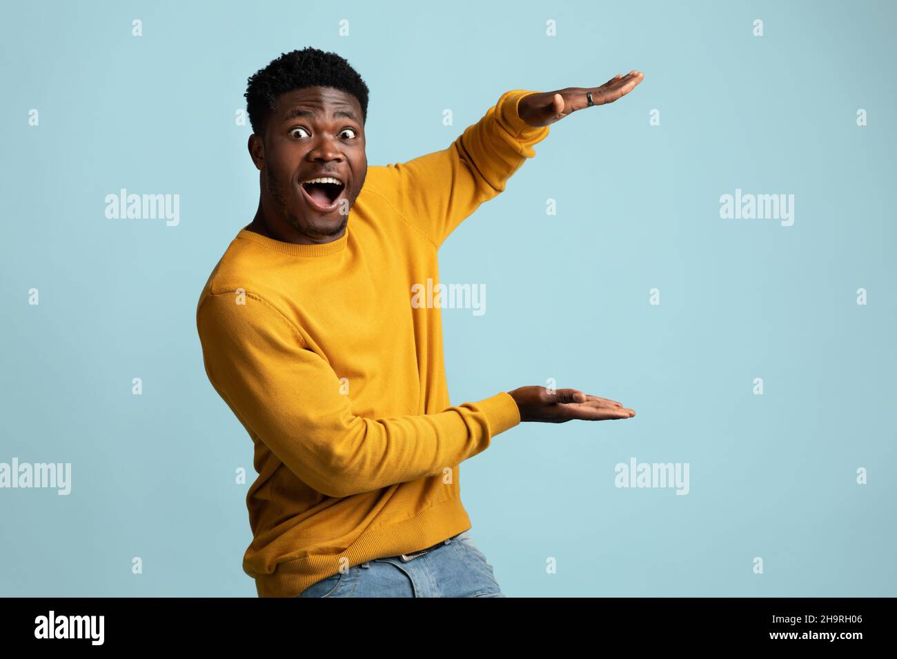 Amazed african american guy holding something invisible Stock Photo - Alamy