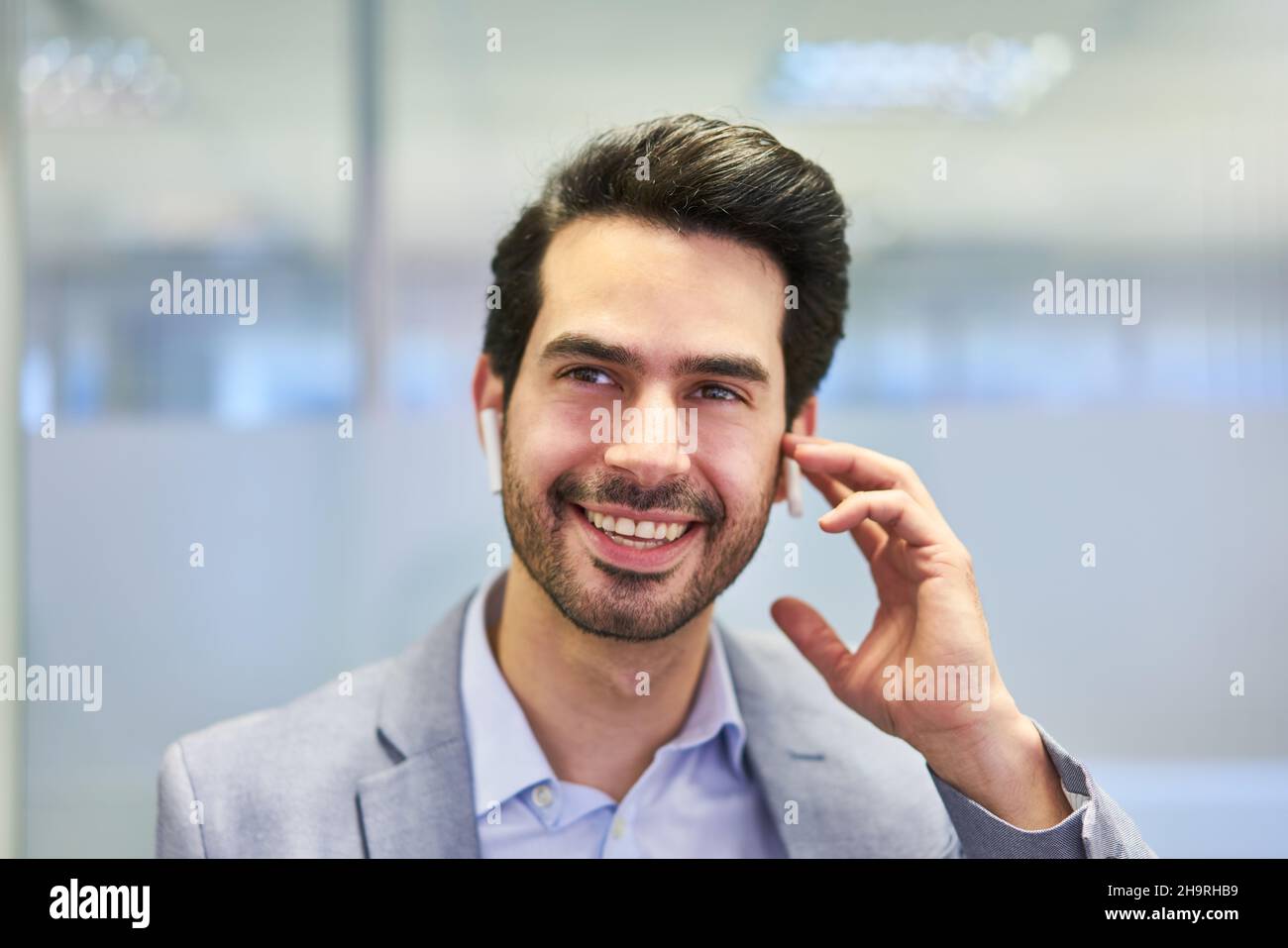 Smiling young businessman using bluetooth headset in mobile ...