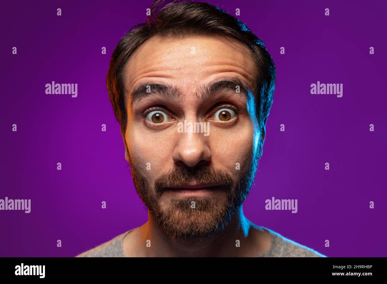 Close-up portrait of man attentivelly looking at camera with eyes wide ...