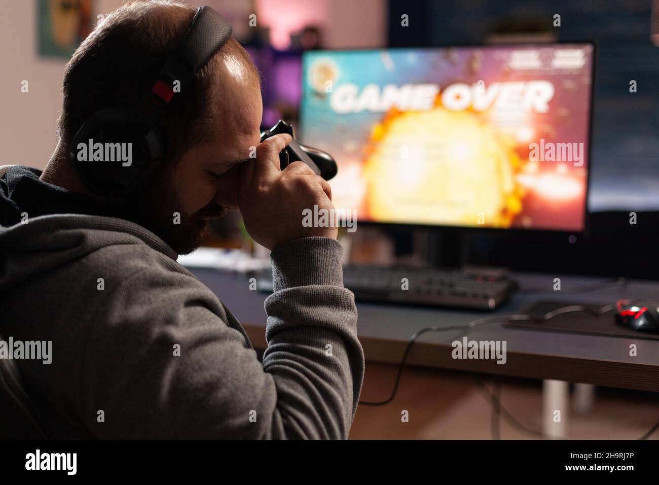 Sad man losing video games after playing with joystick and headphones ...