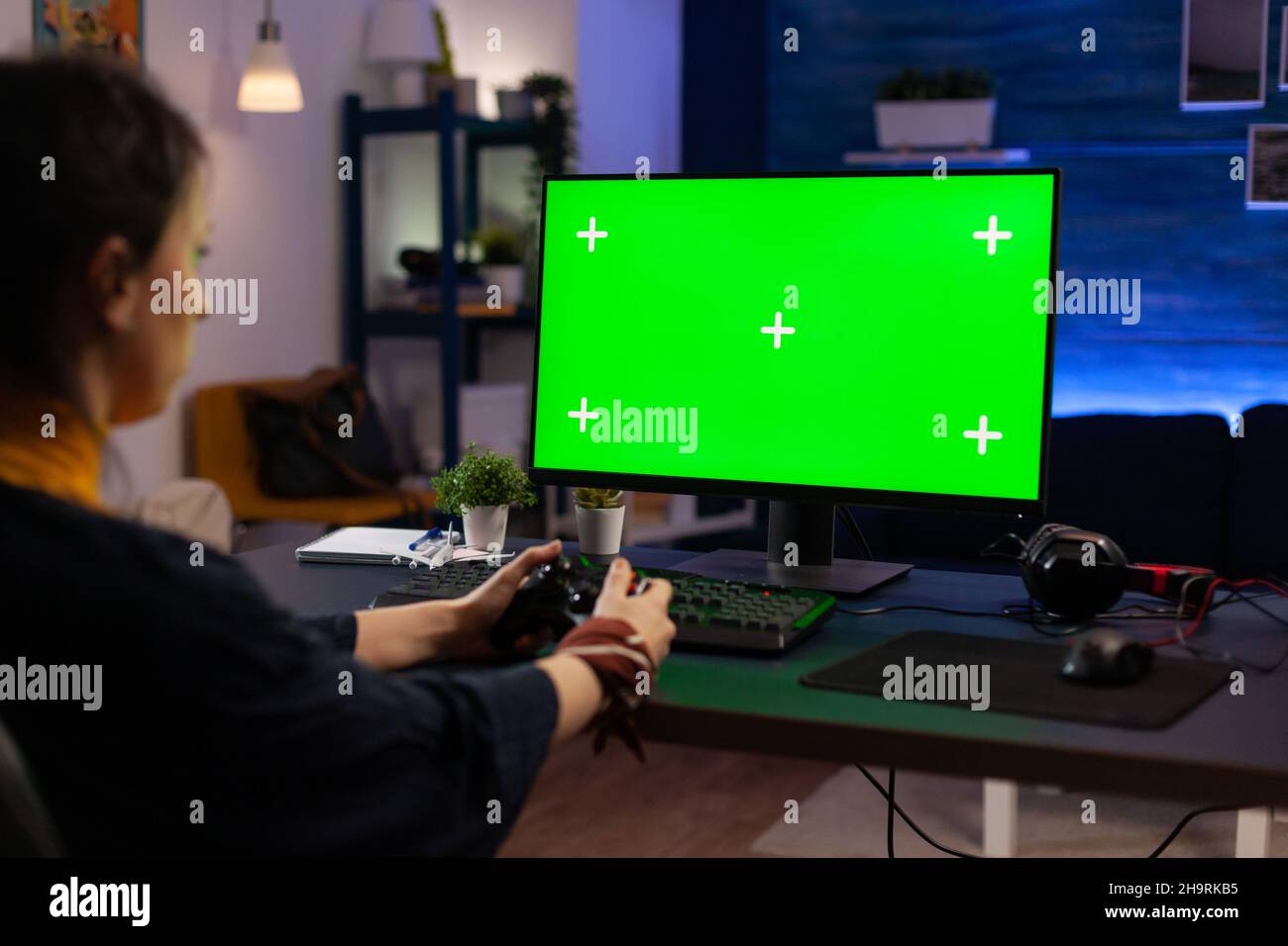 Woman looking at horizontal green screen on monitor, playing video ...