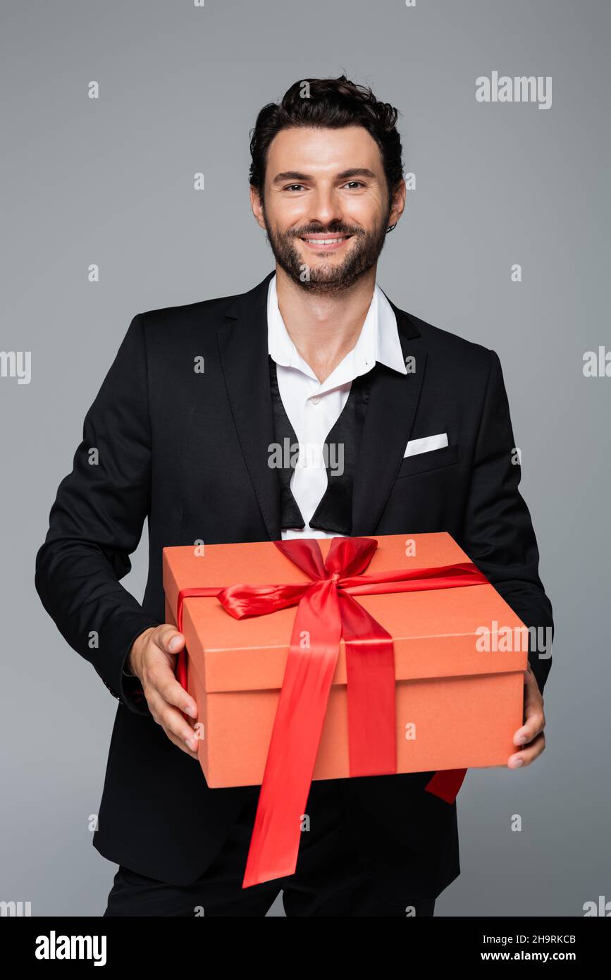 happy man in suit holding red box isolated on grey Stock Photo - Alamy