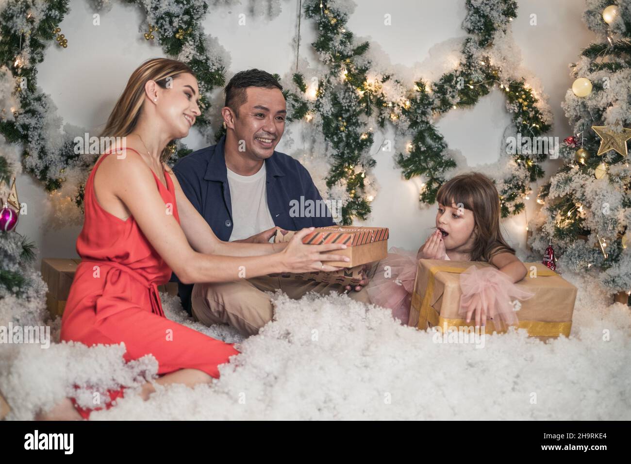 New Year photo of happy mixed family with cute daughter. Parents giving ...