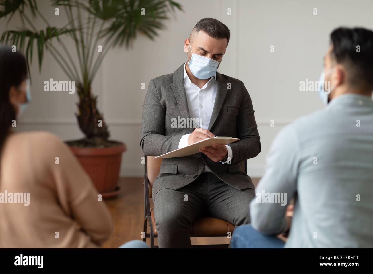 Couple having therapy session with therapist, man writing Stock Photo ...