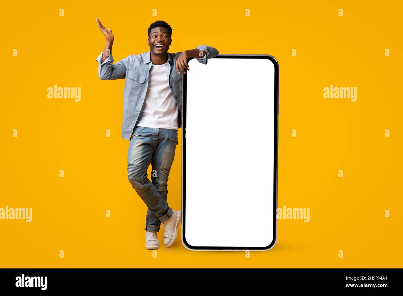 Emotional African American Man Standing By Big Smartphone Mockup Stock