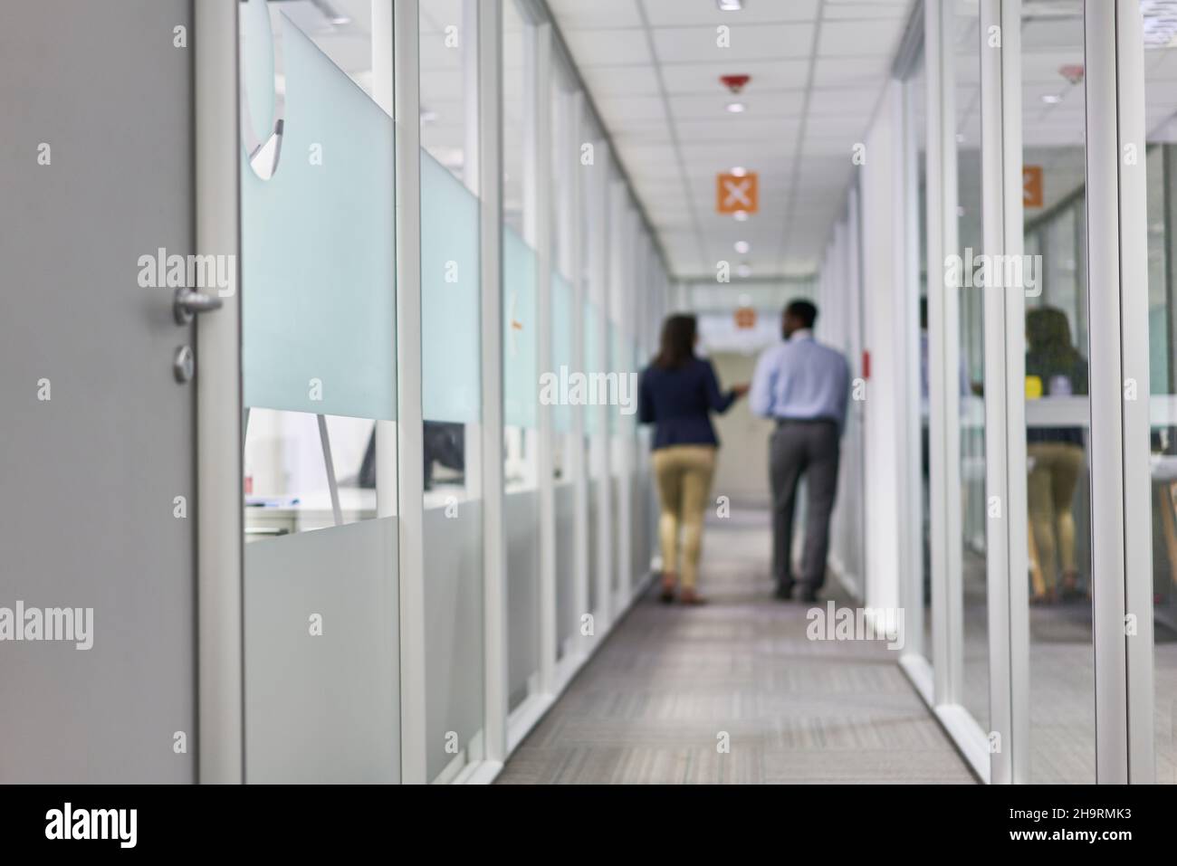 Two business people as colleagues talking to each other in the hallway ...