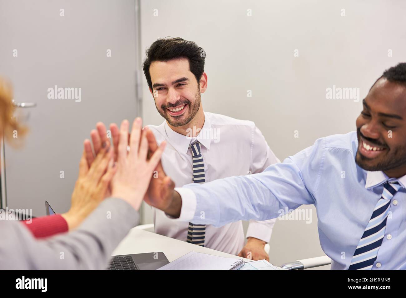 Multicultural business startup team celebrates success with a high five ...