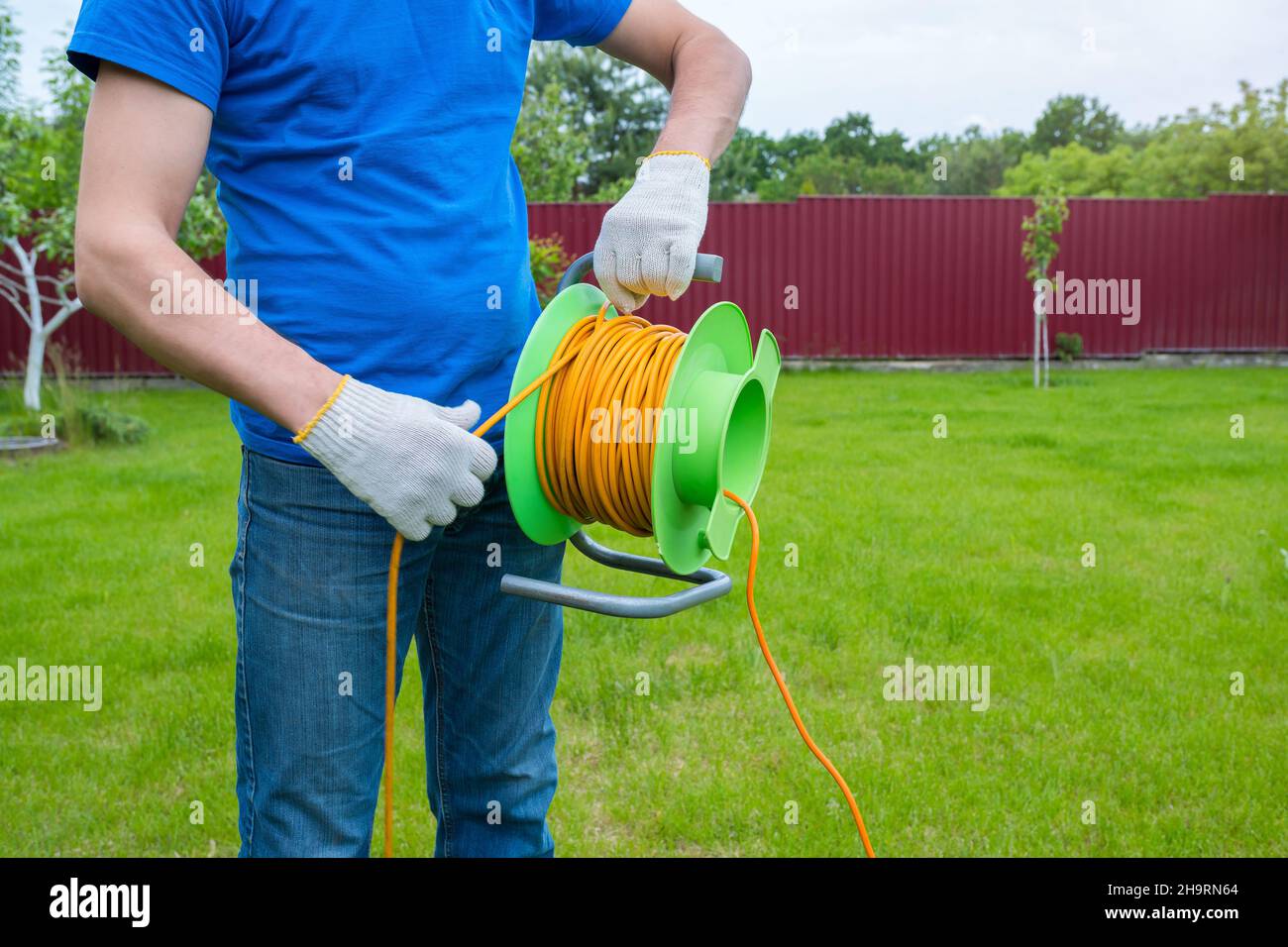 An electrician is unrolling an extension cord on the coil in the house ...