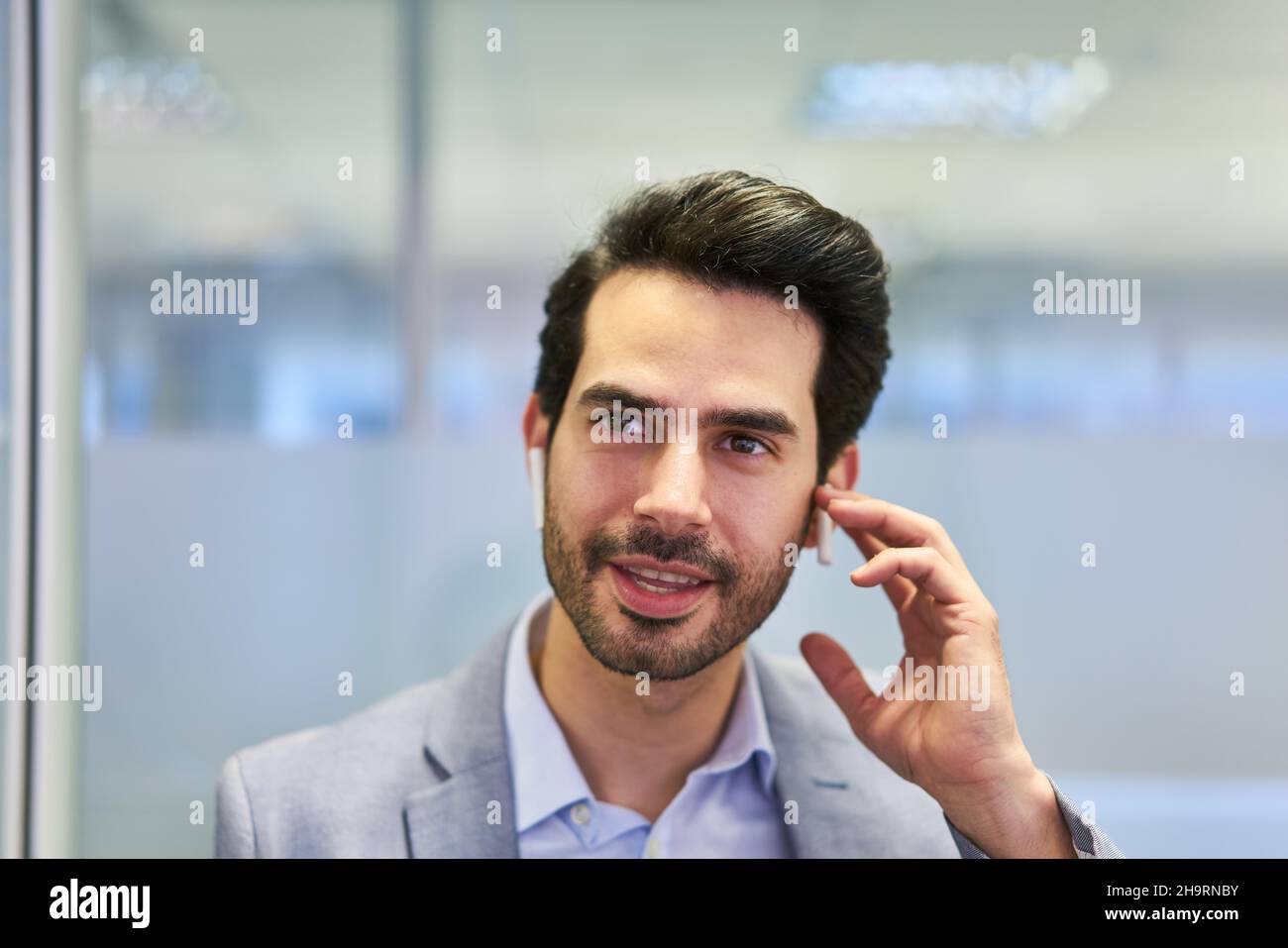 Young start-up business founder listens to positive news with bluetooth ...