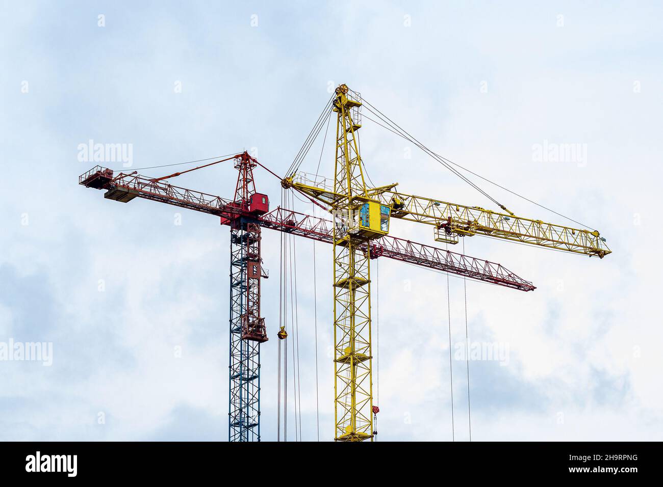 Two high cranes for house building at construction site on blue sky ...