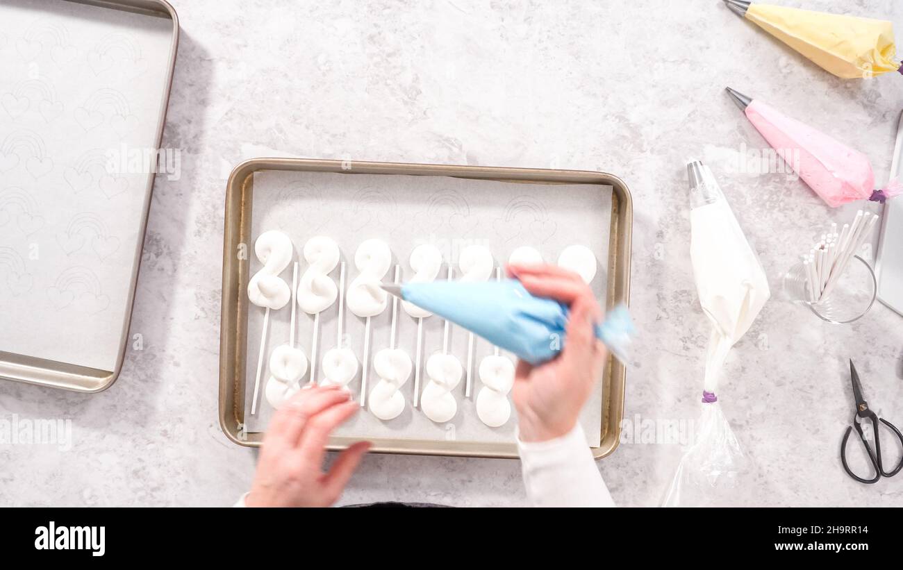 Flat lay. Step by step. Piping meringue mix into unicorn-shaped pops on ...