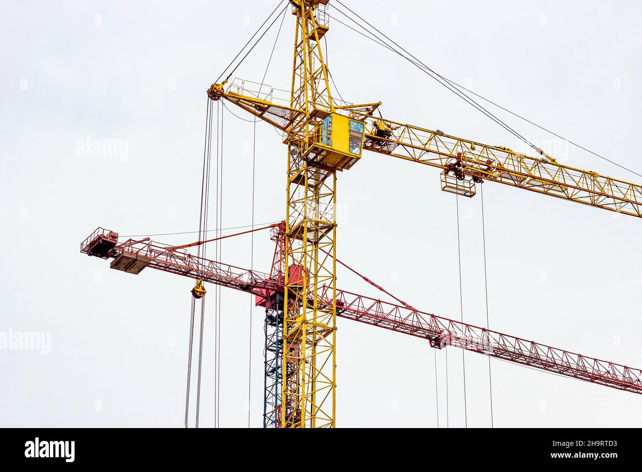 Two high cranes for house building at construction site on sky ...