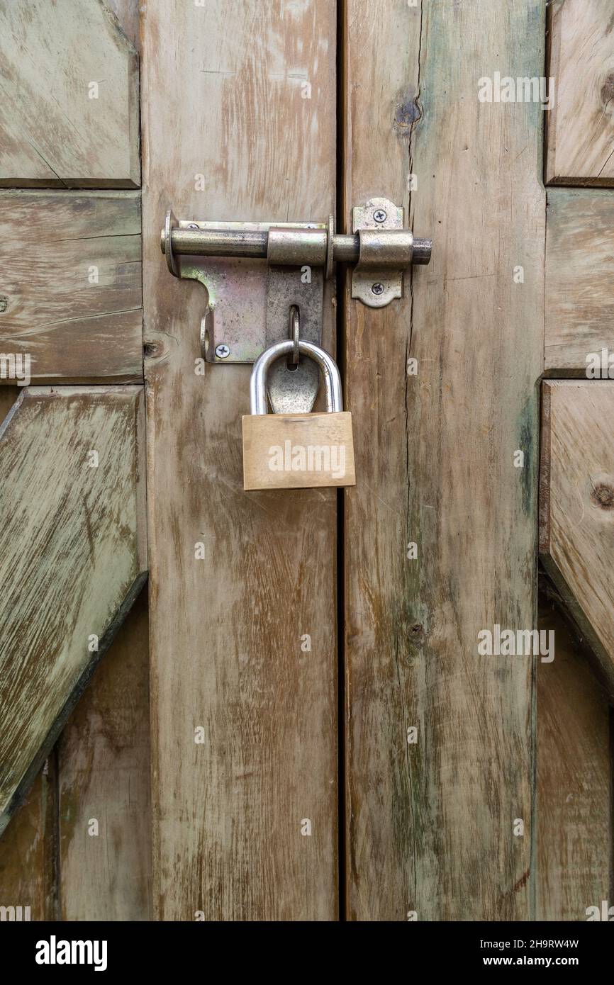 one closed padlock on the pin of a rustic wooden door, metal object ...