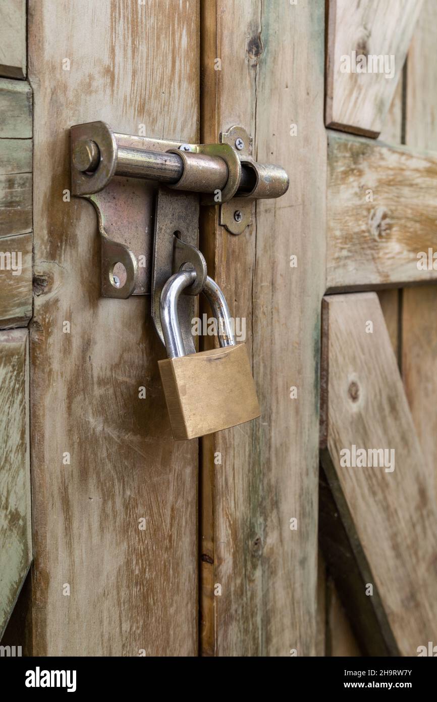 details of one closed padlock on the pin of a rustic wooden door, metal ...