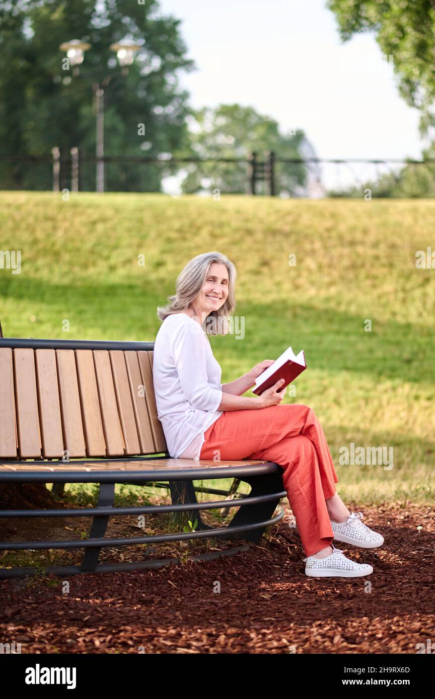 Woman with sitting on bench sideways turned face to camera Stock Photo ...