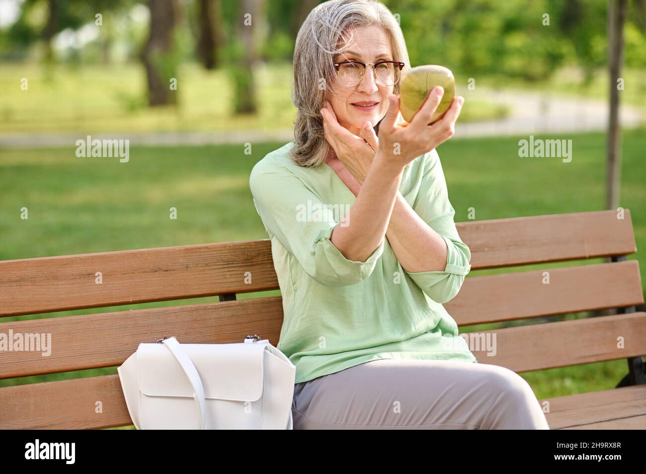 Elegant woman looking in mirror on bench Stock Photo - Alamy