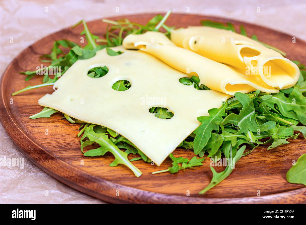Fresh yellow swiss cheese rolled slices on green arugula leaves on ...