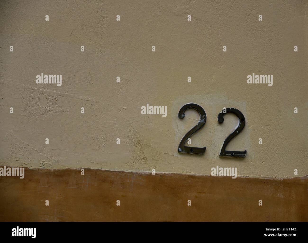 Antique brass street numbers on a two-tone ochre stucco wall in Nafplio ...
