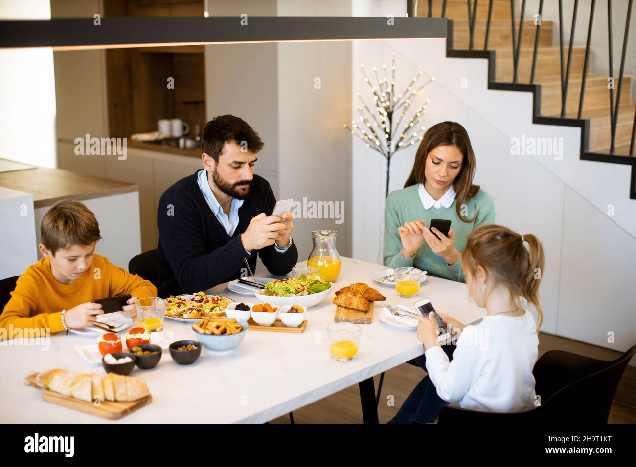 Family using mobile phones while having breakfast at dining table at ...