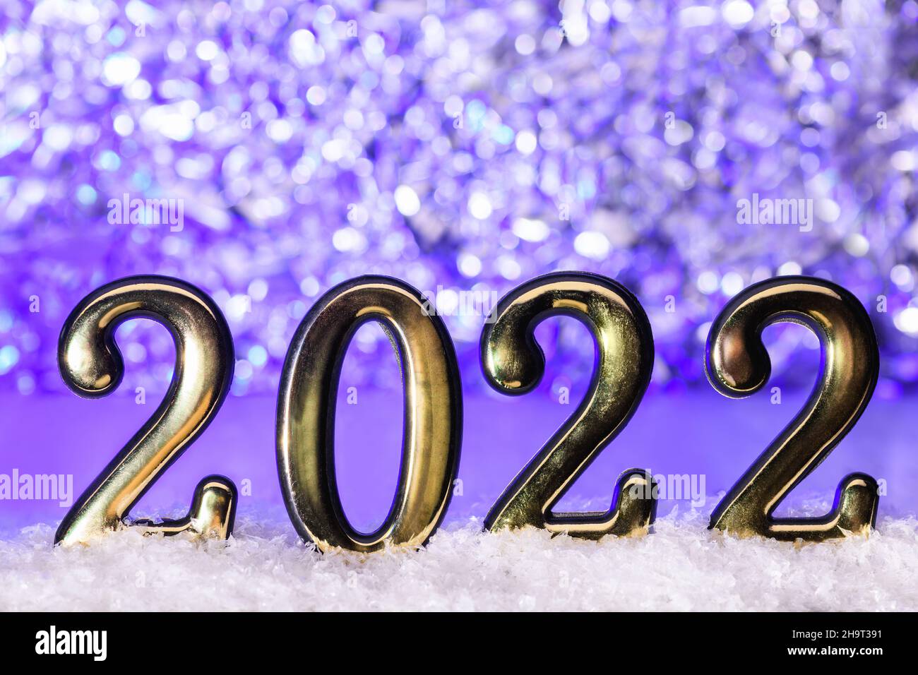 Gold numbers 2022 on snow with purple backlight. New year backdrop with ...