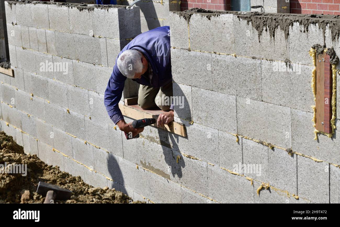 The mason screws a wood plank into the wall at the construction site ...