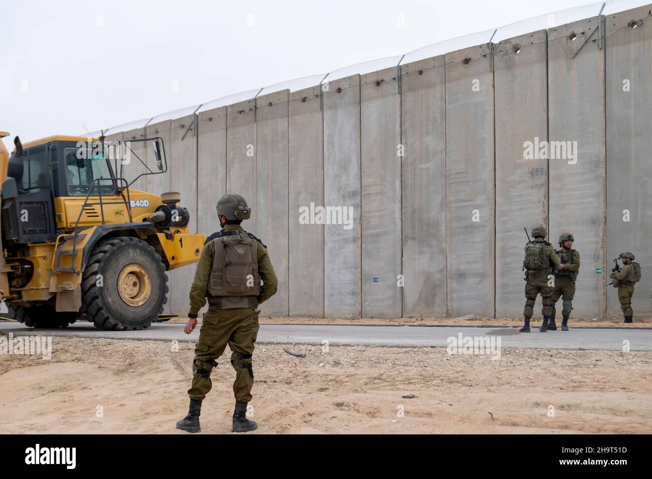 Israeli soldiers stand guard next to a concrete border wall at the ...