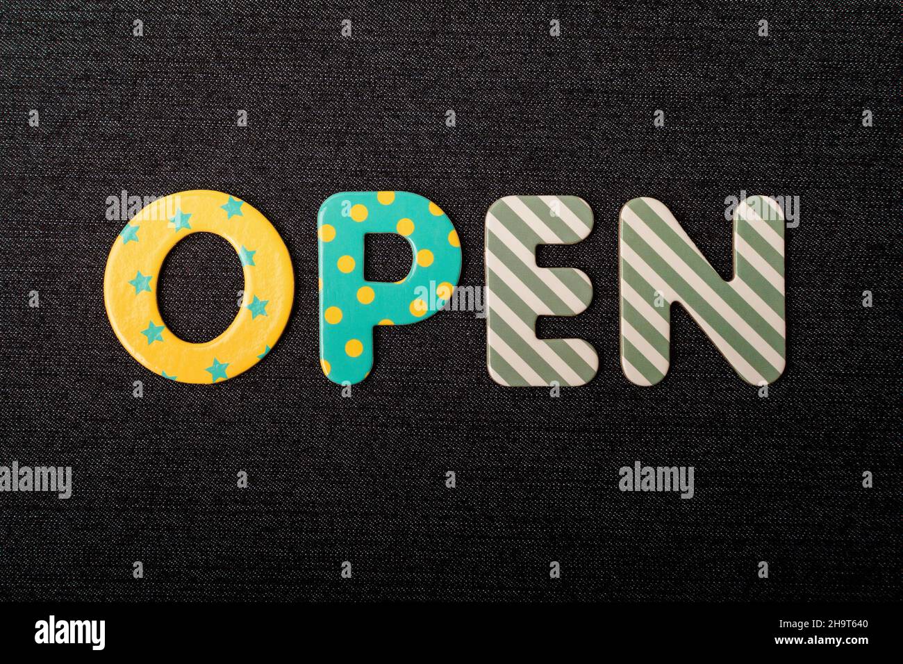 Card with Open word made from mixed vivid colored wooden letters on a ...