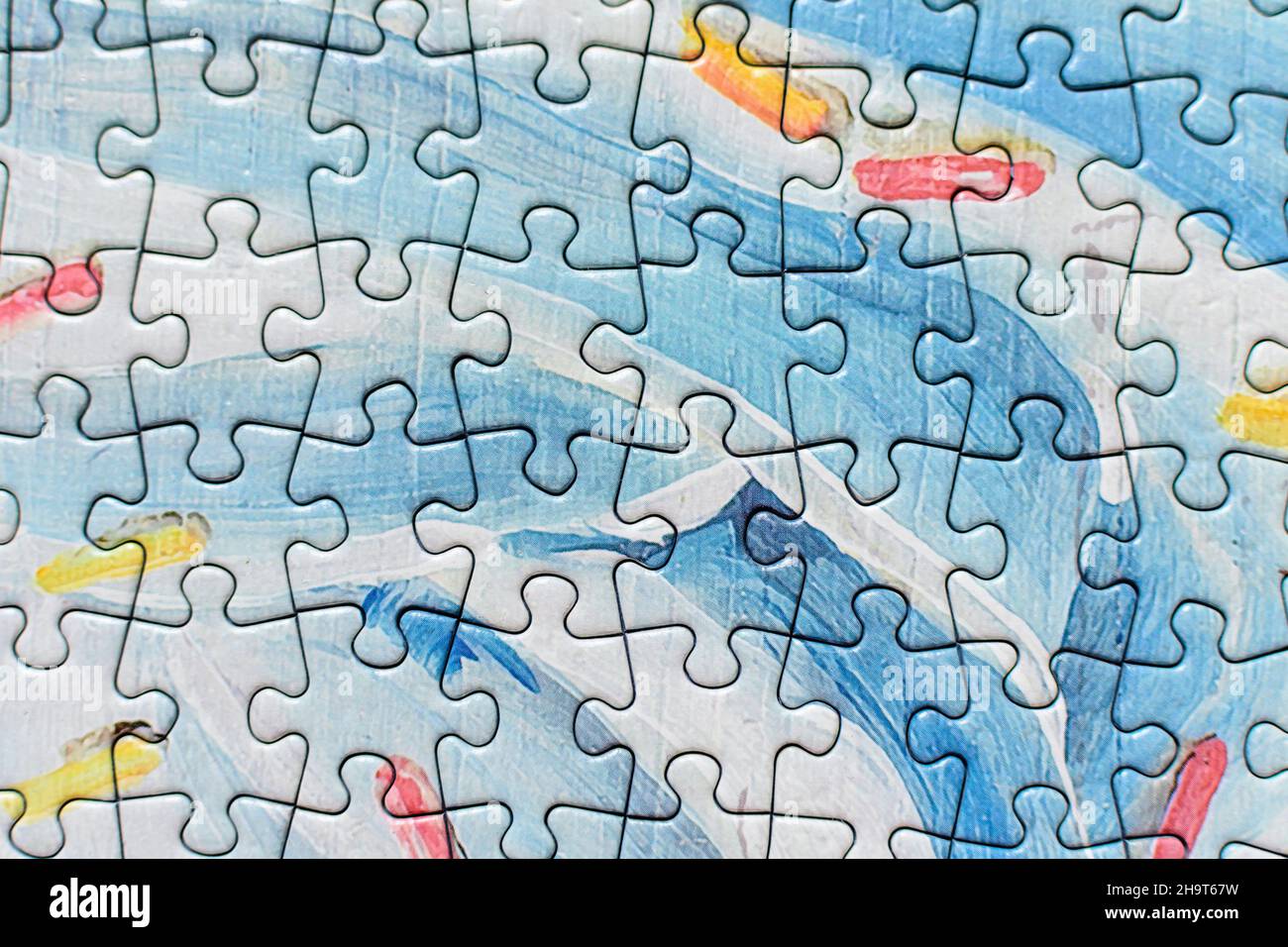Many light grey and blue textured cardboard puzzle pieces on a table ...