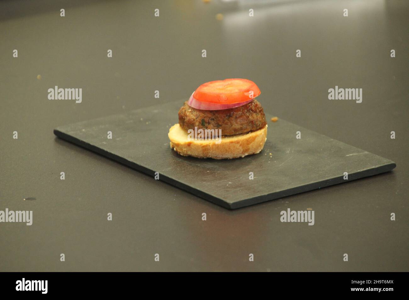 Deconstructed gourmet burger with a tomato and a patty Stock Photo - Alamy